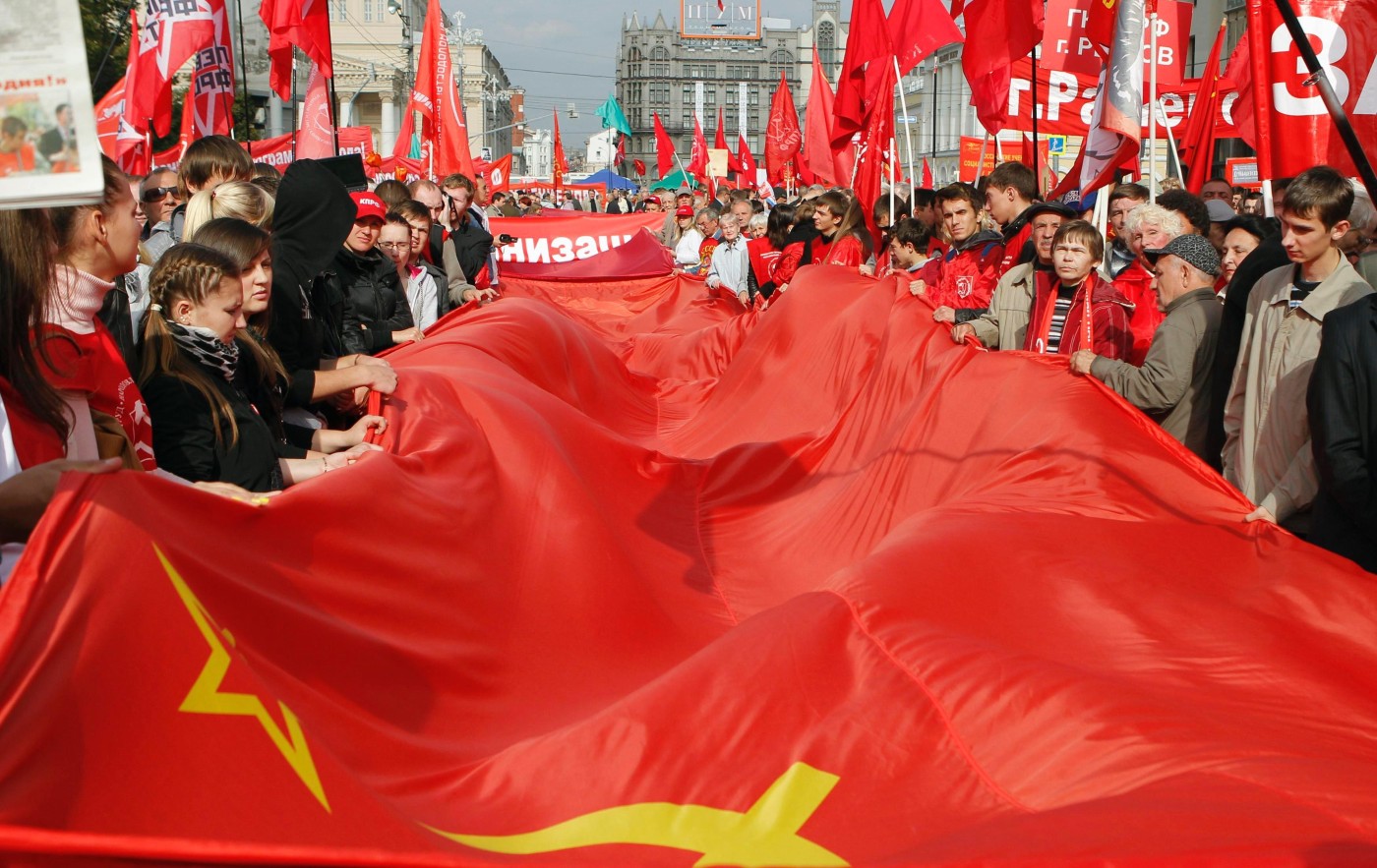 Participants hold a large flag with the communist insignia during a ...