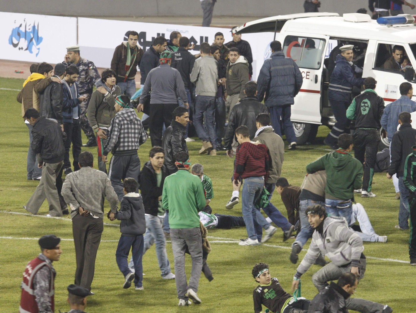 Injured fans of Al Wehdat rest on the pitch after clashing with ...