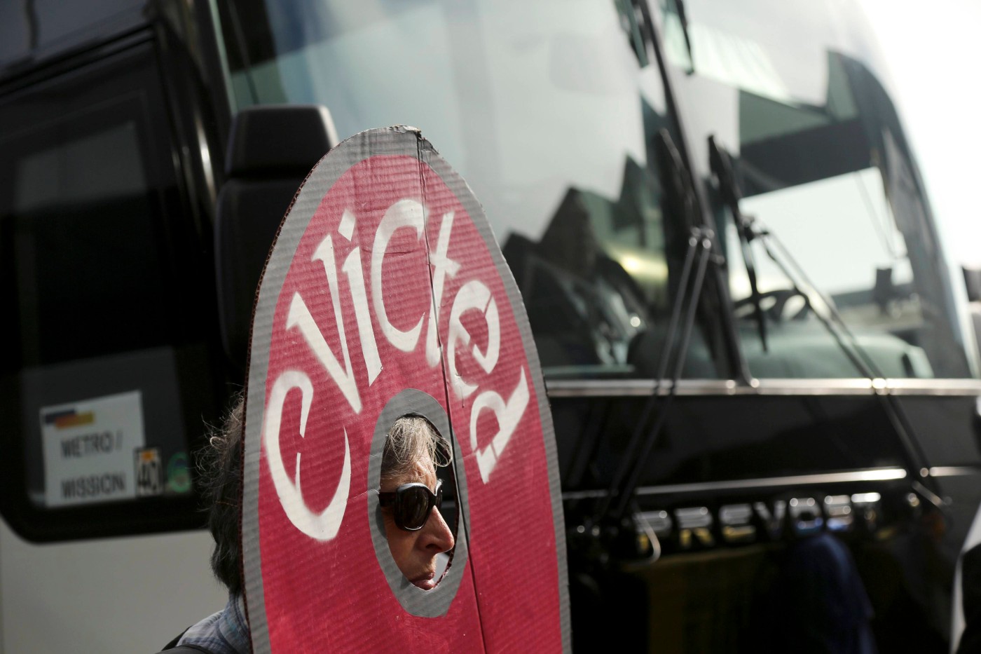 A demonstrator with a sign stands in the path of a Google commuter bus ...
