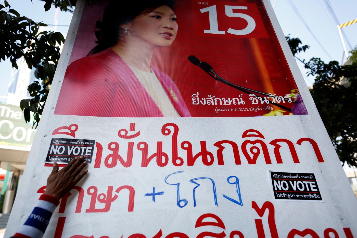An anti-government protester pastes a "No Vote" sticker on a pre ...