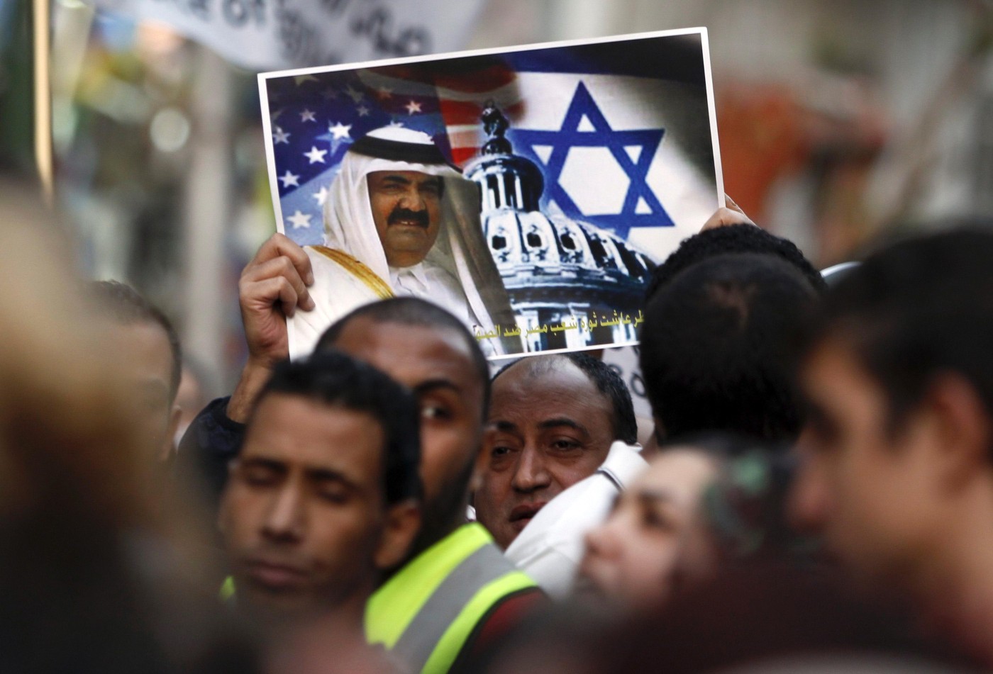 A protester holds a sign against Qatar and Israel during a protest ...
