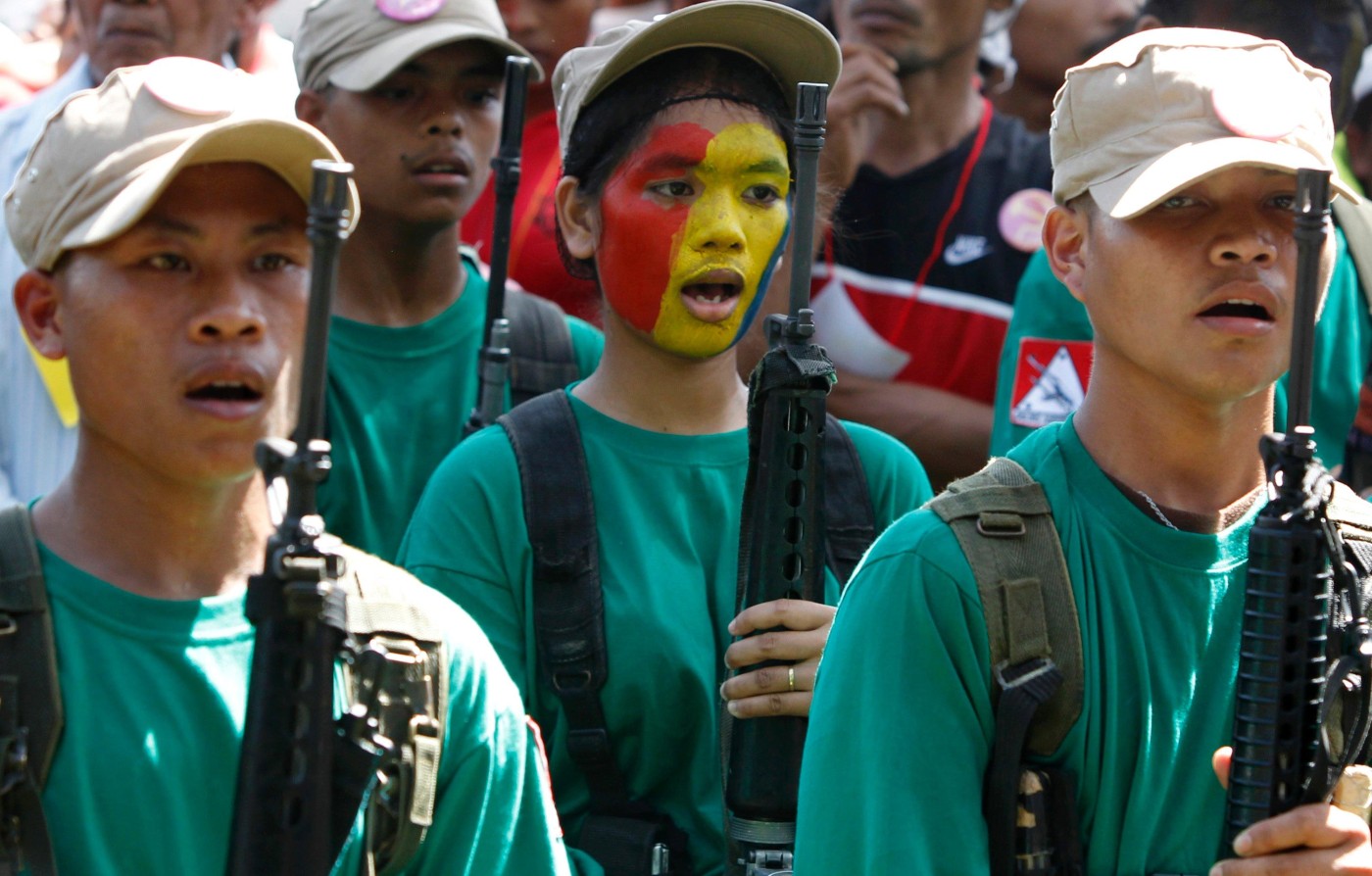 Filipino communist rebels hold their weapons while singing communist ...