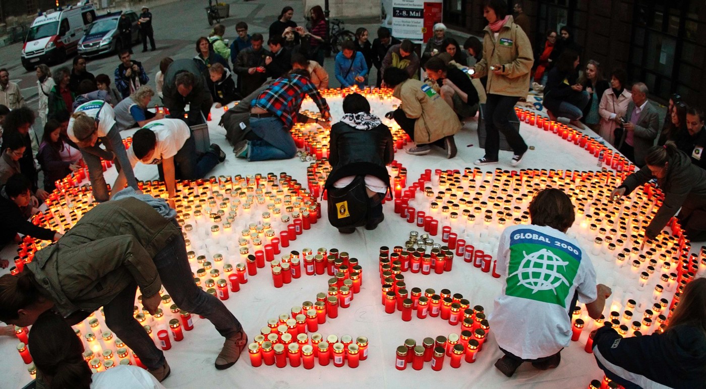 Activists light candles to display a nuclear radiation warning sign ...