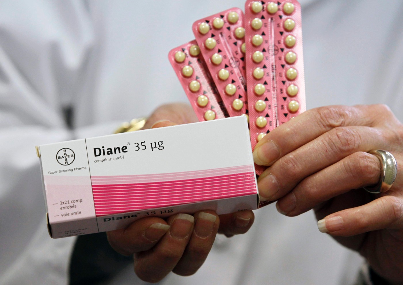 A chemist holds a box and blister-packs of acne drug Diane-35, which is ...