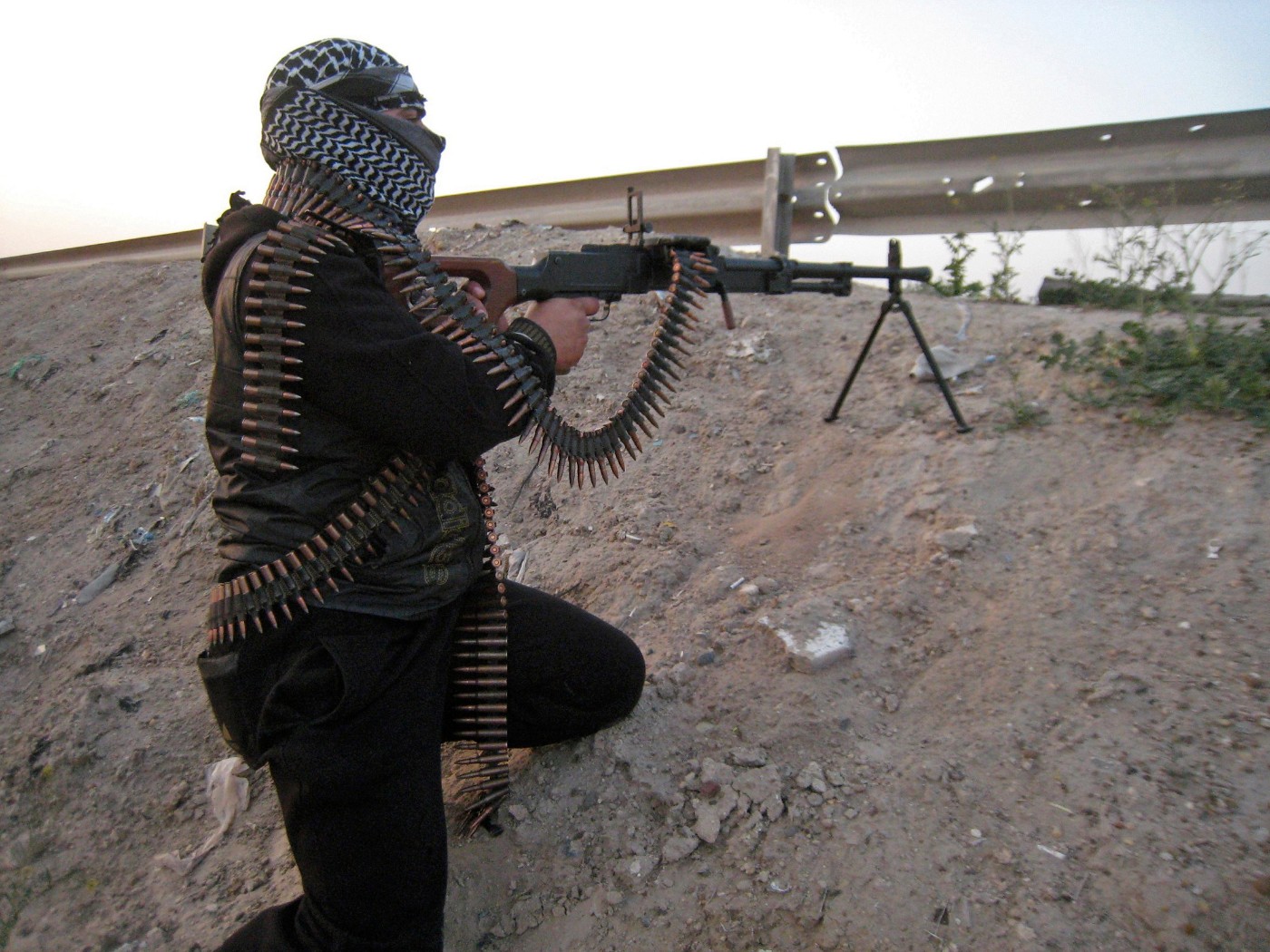 A masked Sunni Muslim gunman takes up position with his weapon during ...
