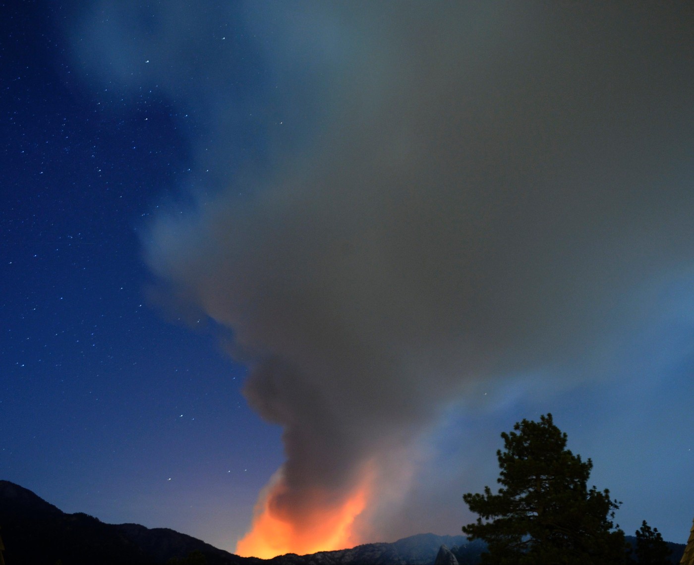 A plume of smoke rises into the night sky as a wildfire, or the so ...