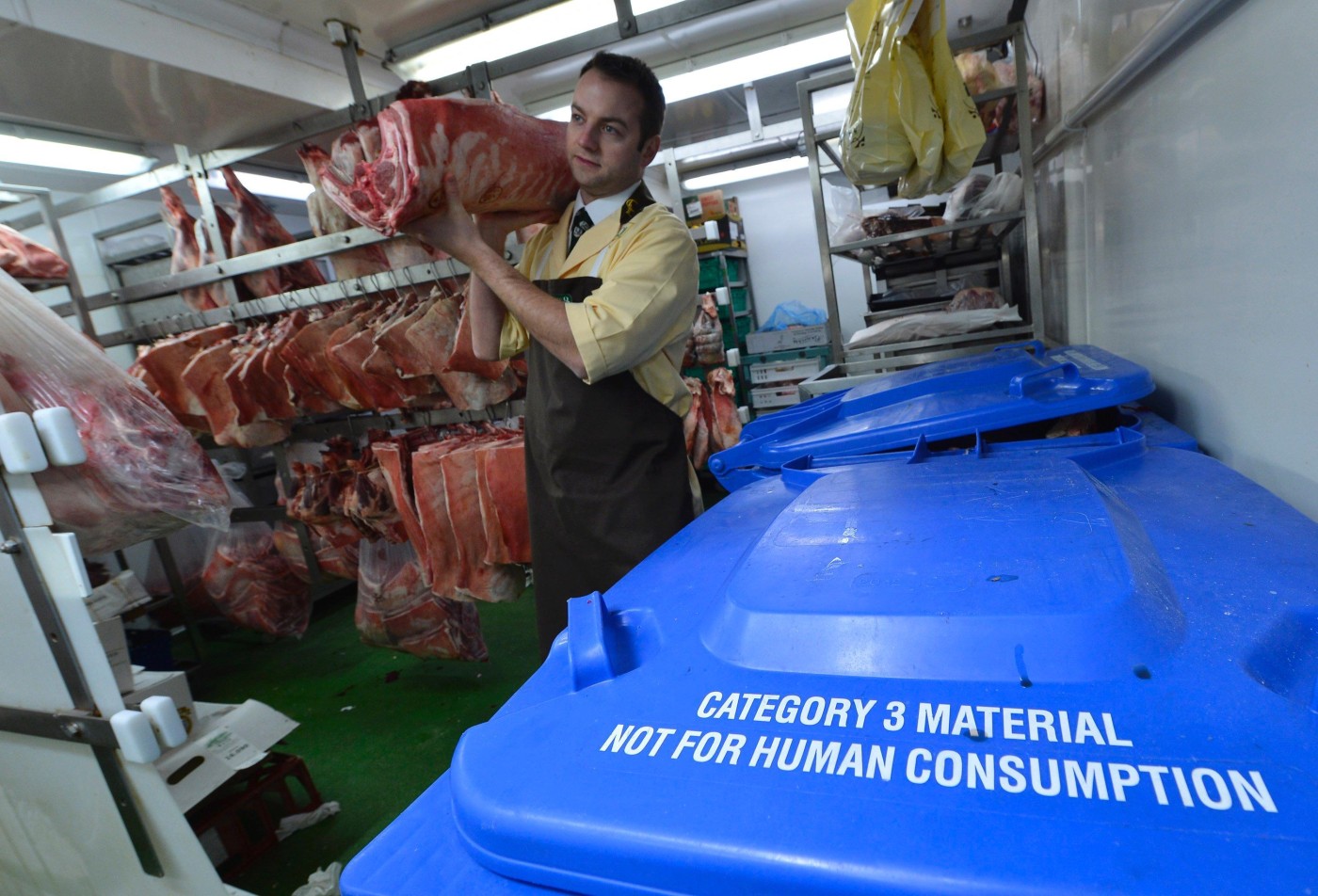 Danny Lidgate carries meat past a waste bin in the cold store area of ...