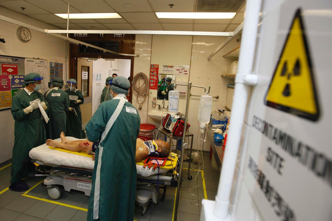 Medical personnel inspect a man acting as a patient contaminated with ...