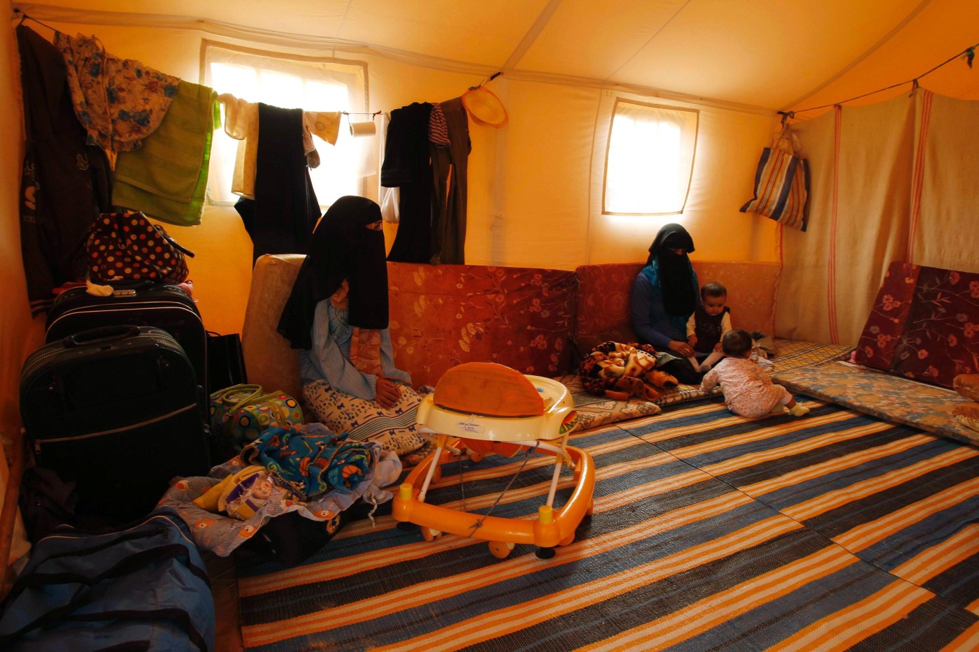 Libyan refugees who fled unrest in Libya sit inside their tent at a ...