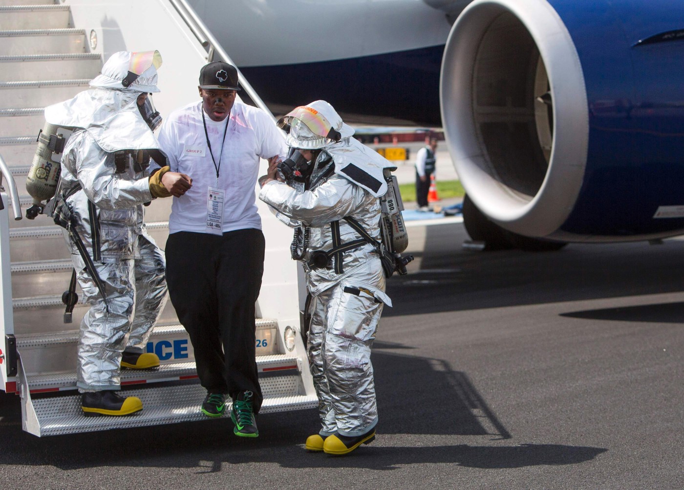 Emergency rescue workers assist an actor posing as an injured passenger ...