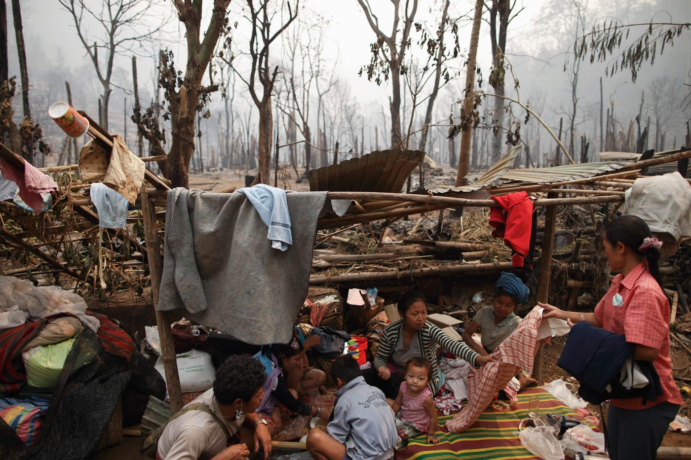 Survivors sit in their temporary shelter in the fire gutted Ban Mae ...