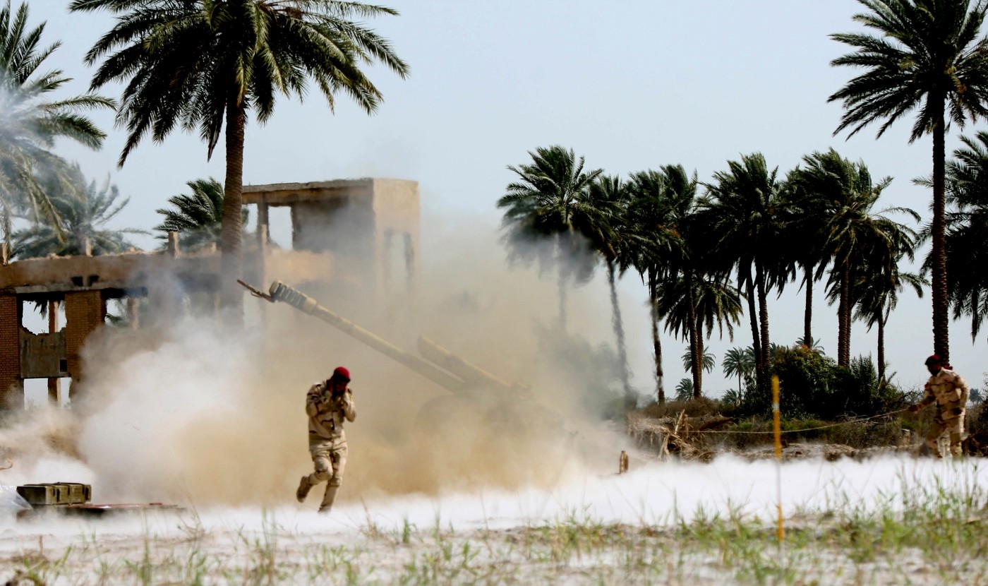 Iraqi security forces fire an artillery during clashes with the al ...